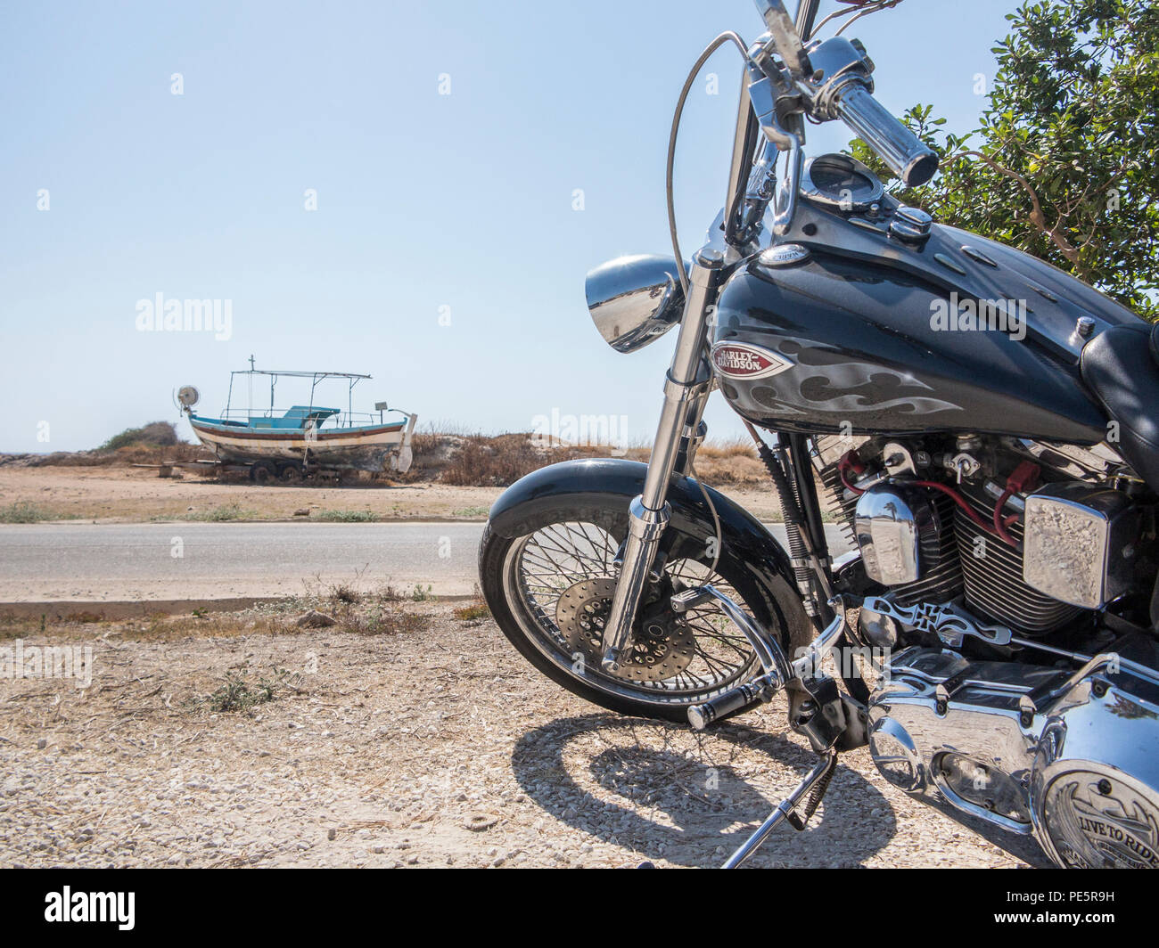 A Harley Davidson motorbike with a fishing boat in the distance on the ...