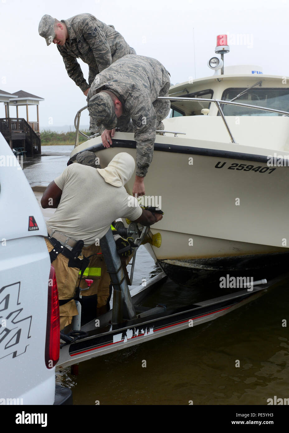 U.S. Air Force Airmen align a fire and rescue boat with a hitch to tow ...