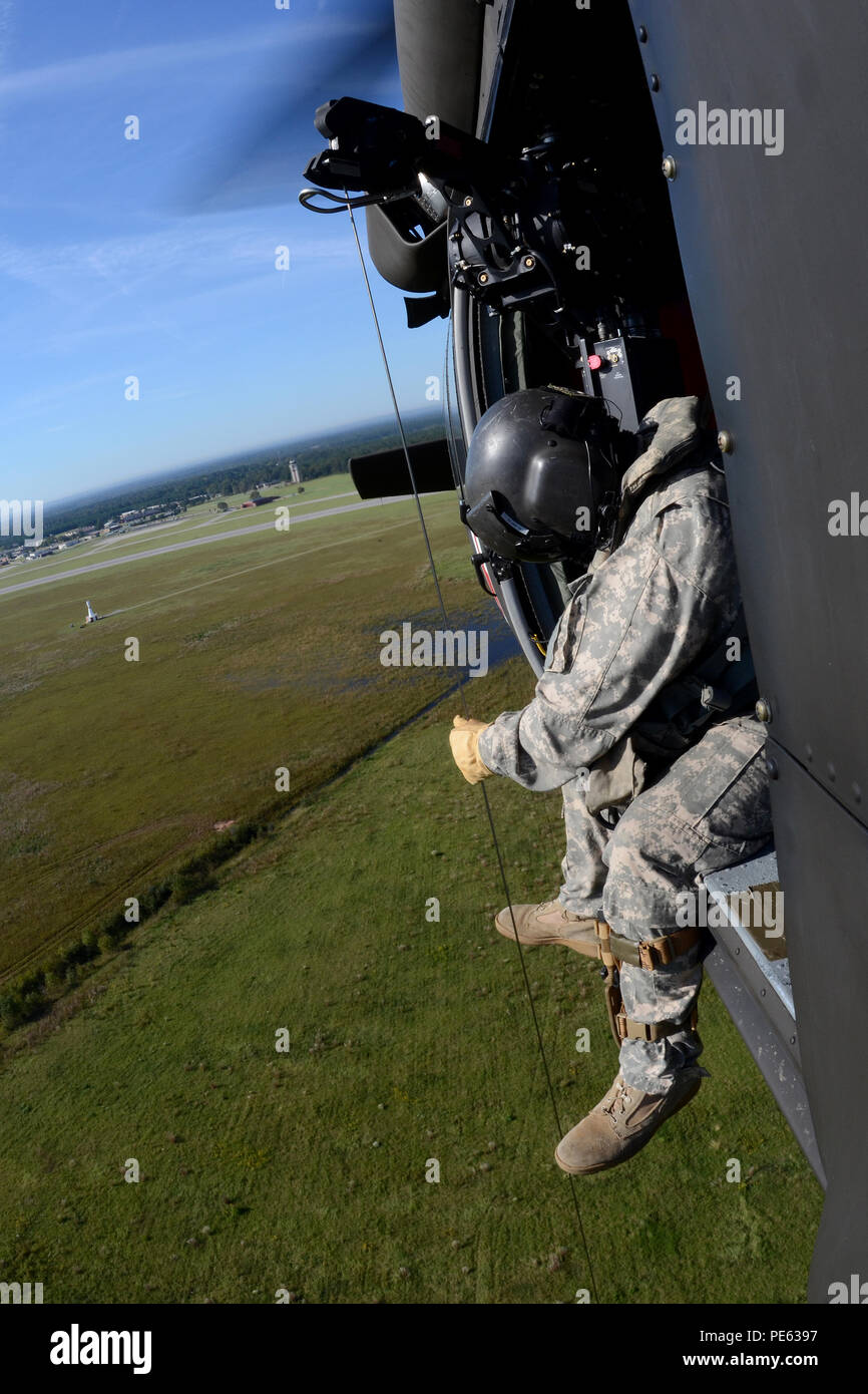 A U.S. Army UH-60 Black Hawk helicopter crew chief braces a hoist line ...