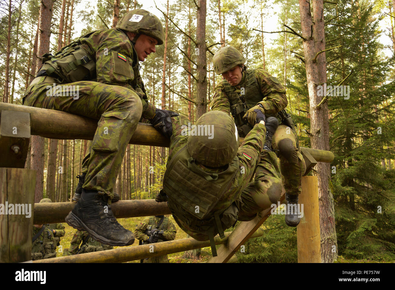 Lithuanian soldiers work together to get over an obstacle at the ...