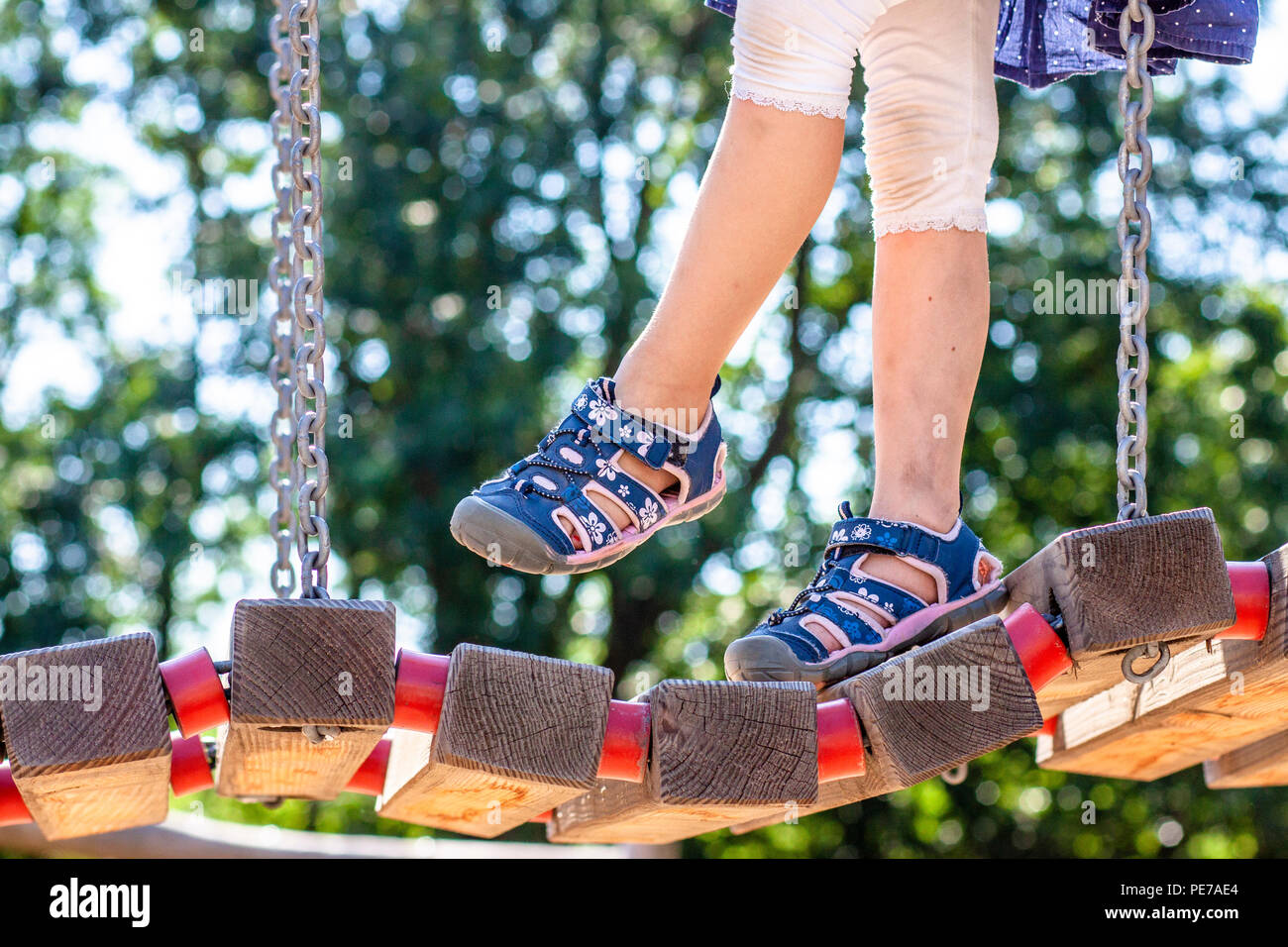 Little girl with sandal walking over bridge Stock Photo - Alamy