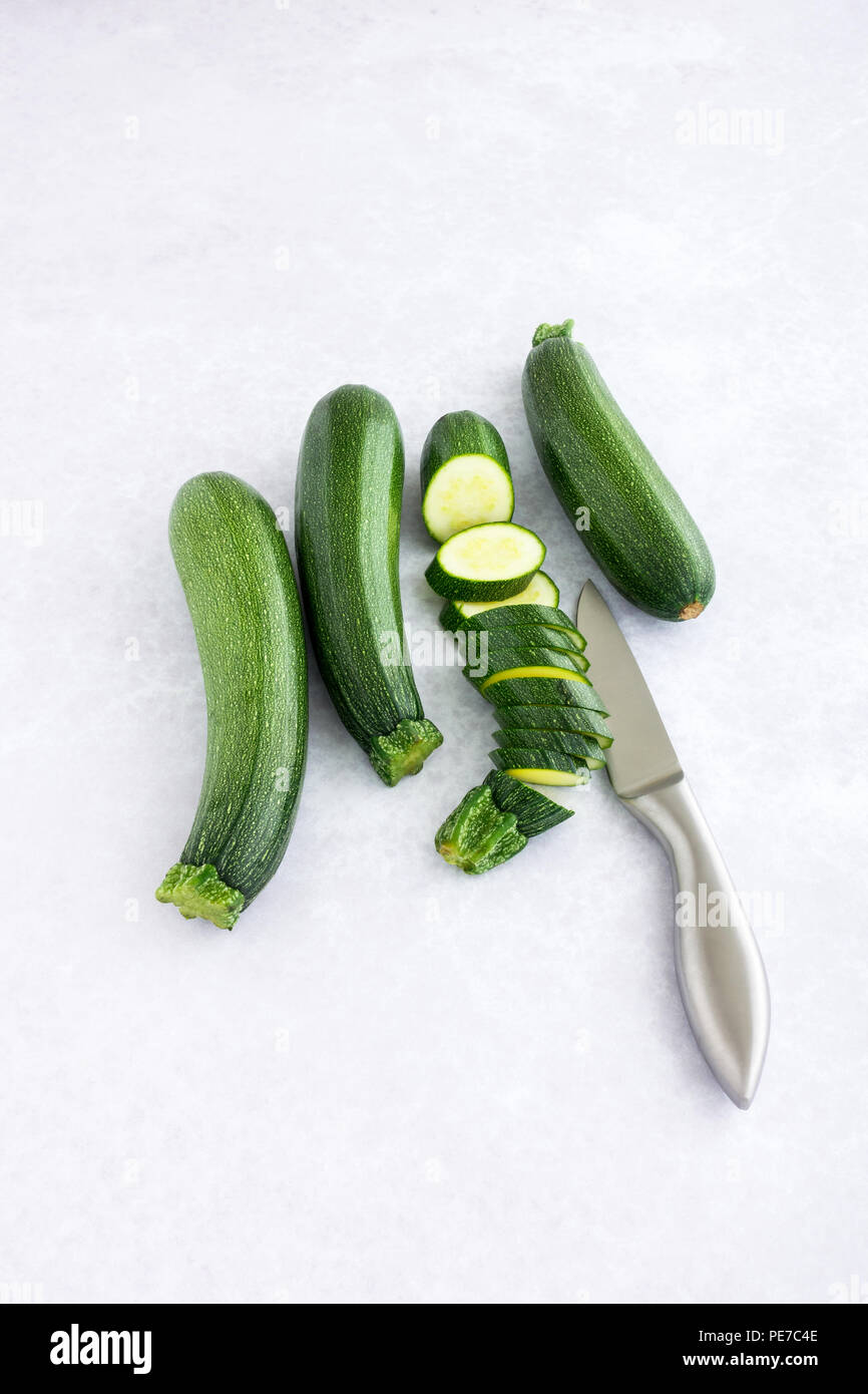 Whole and cut zucchini with knife on gray background with lots of copy ...
