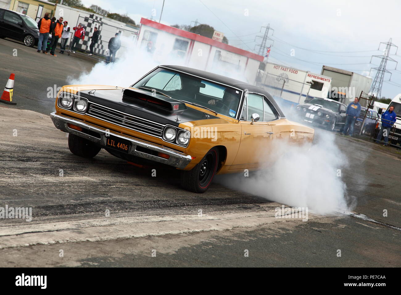 A car performing a wheel spin to warm up the tyres before racing on the ...