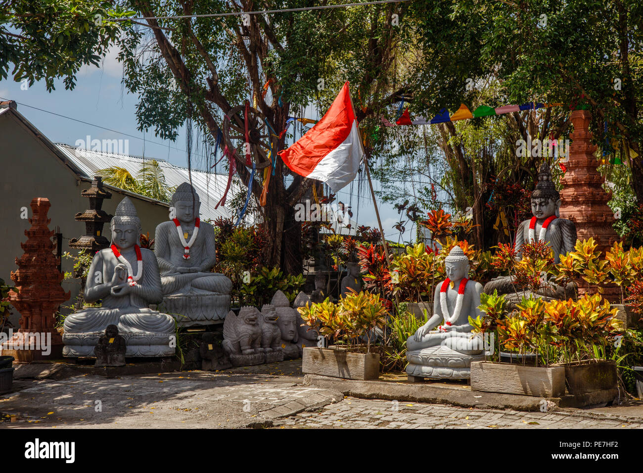 Stone statues of Sitting Buddhas, with garlands in red and white colors ...