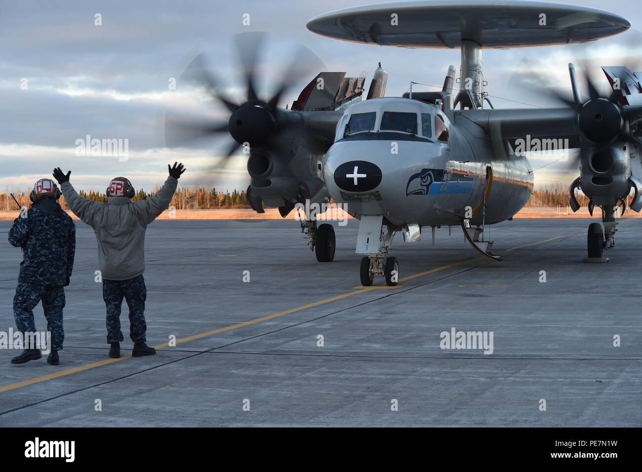 U.S. Navy seaman directs a U.S. Navy E-2 Hawkeye on the flight line ...