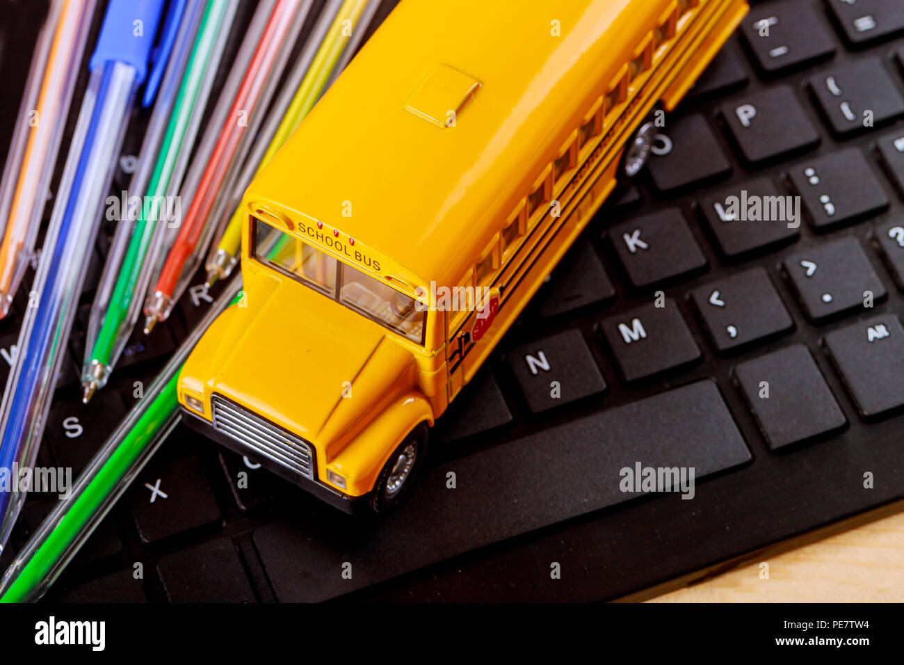 A yellow toy school bus and colored pencils on a keyboard computer ...