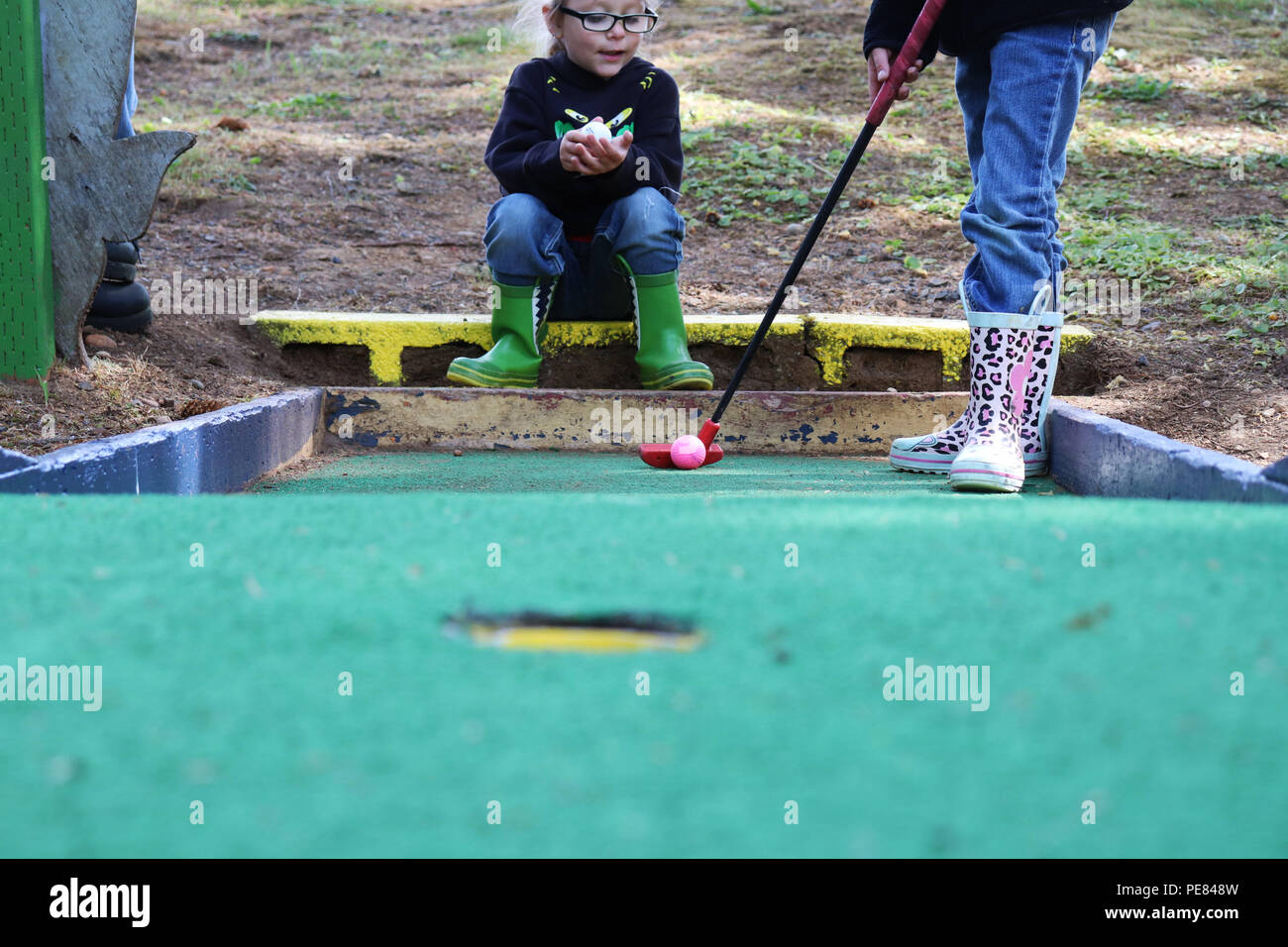 Two children playing mini golf in the spring Stock Photo - Alamy