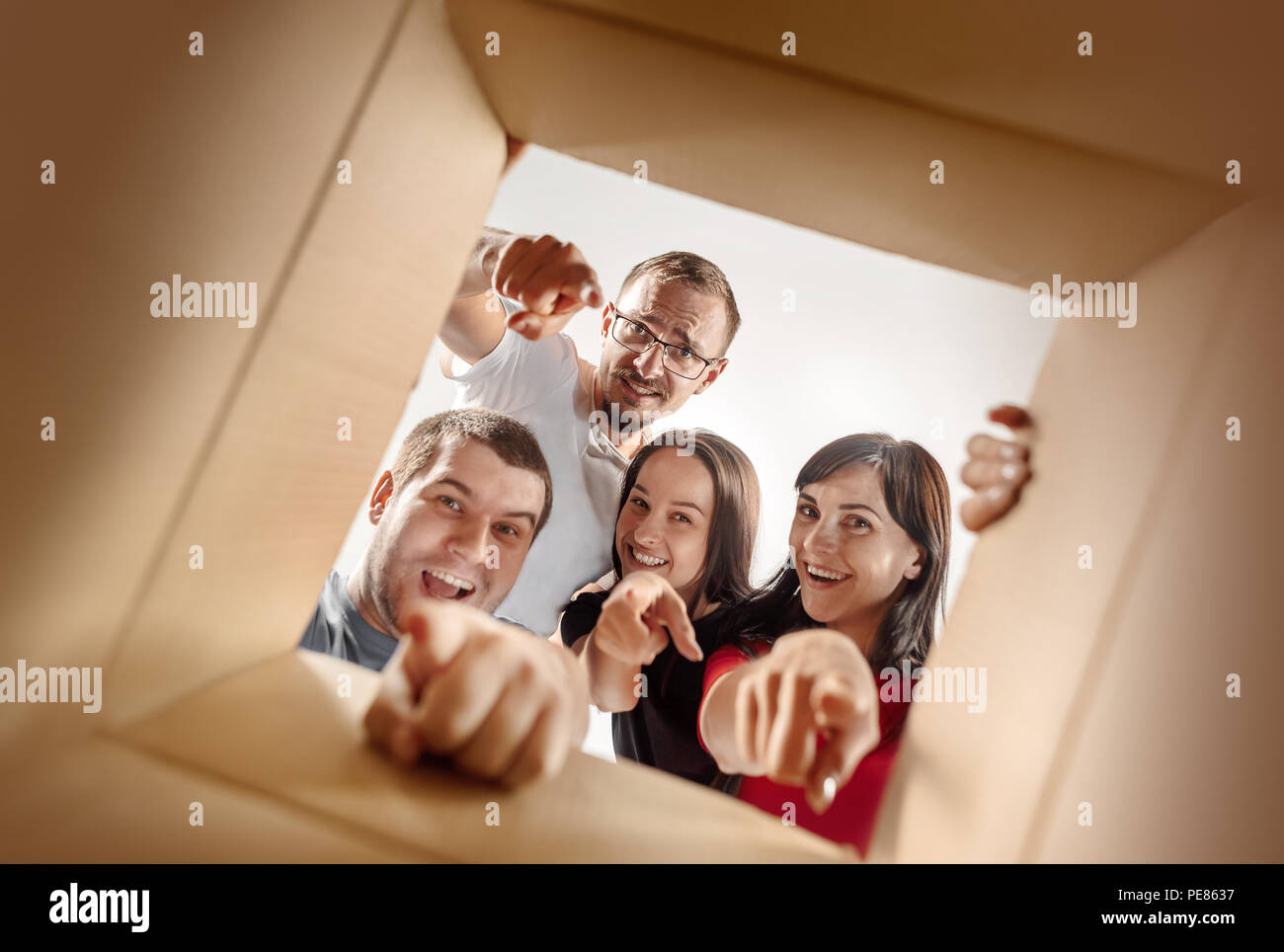 The surprised caucasian men and women opening carton box and looking ...