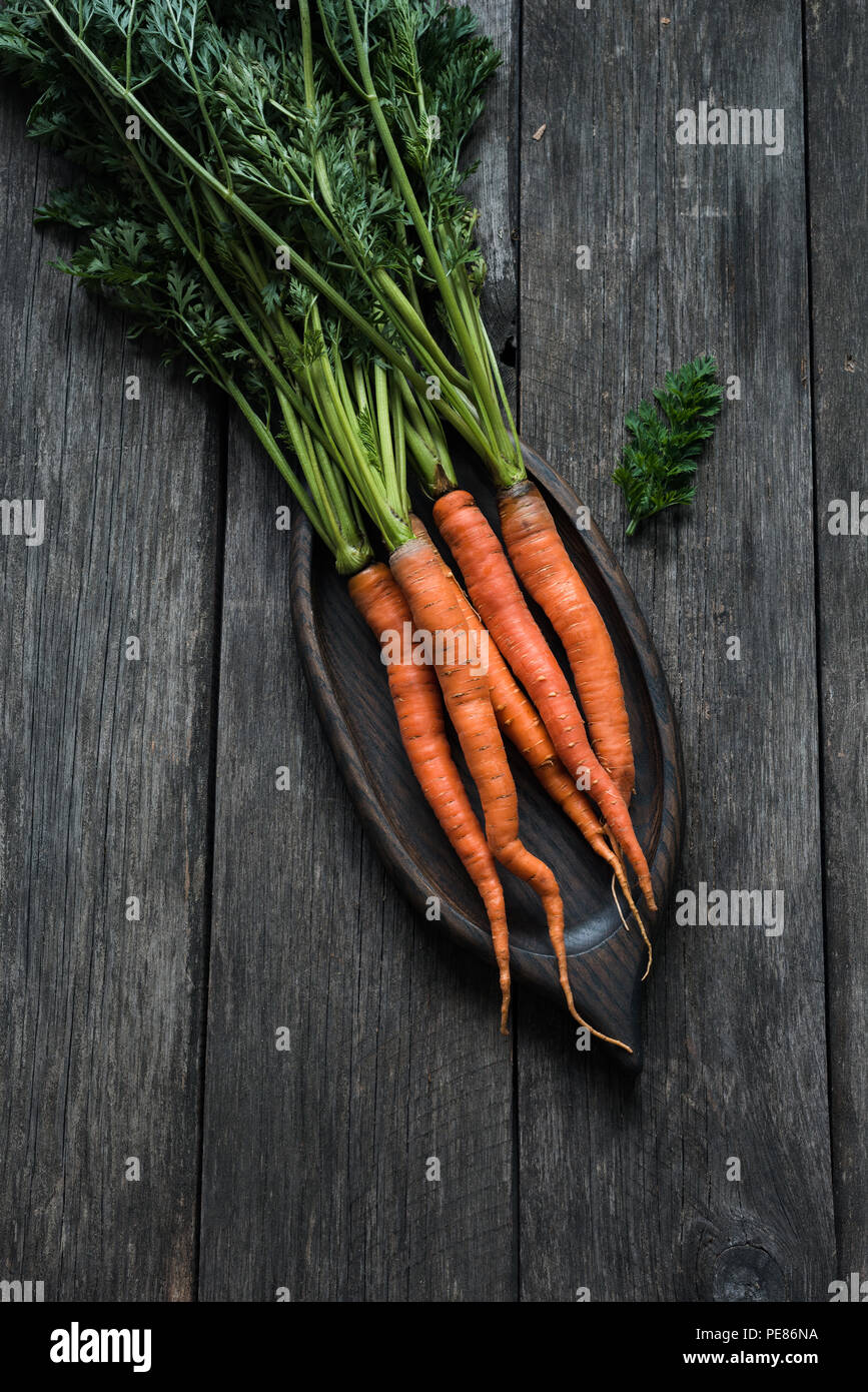Fresh carrots on wooden table. Organic farm root vegetable harvest ...