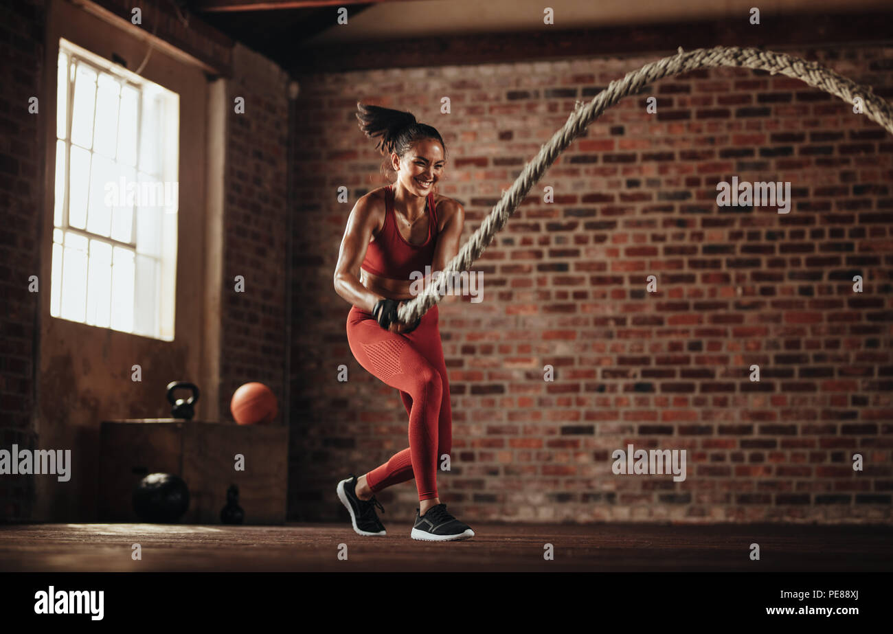 Strong female athlete working out with battling rope at gym. Healthy ...