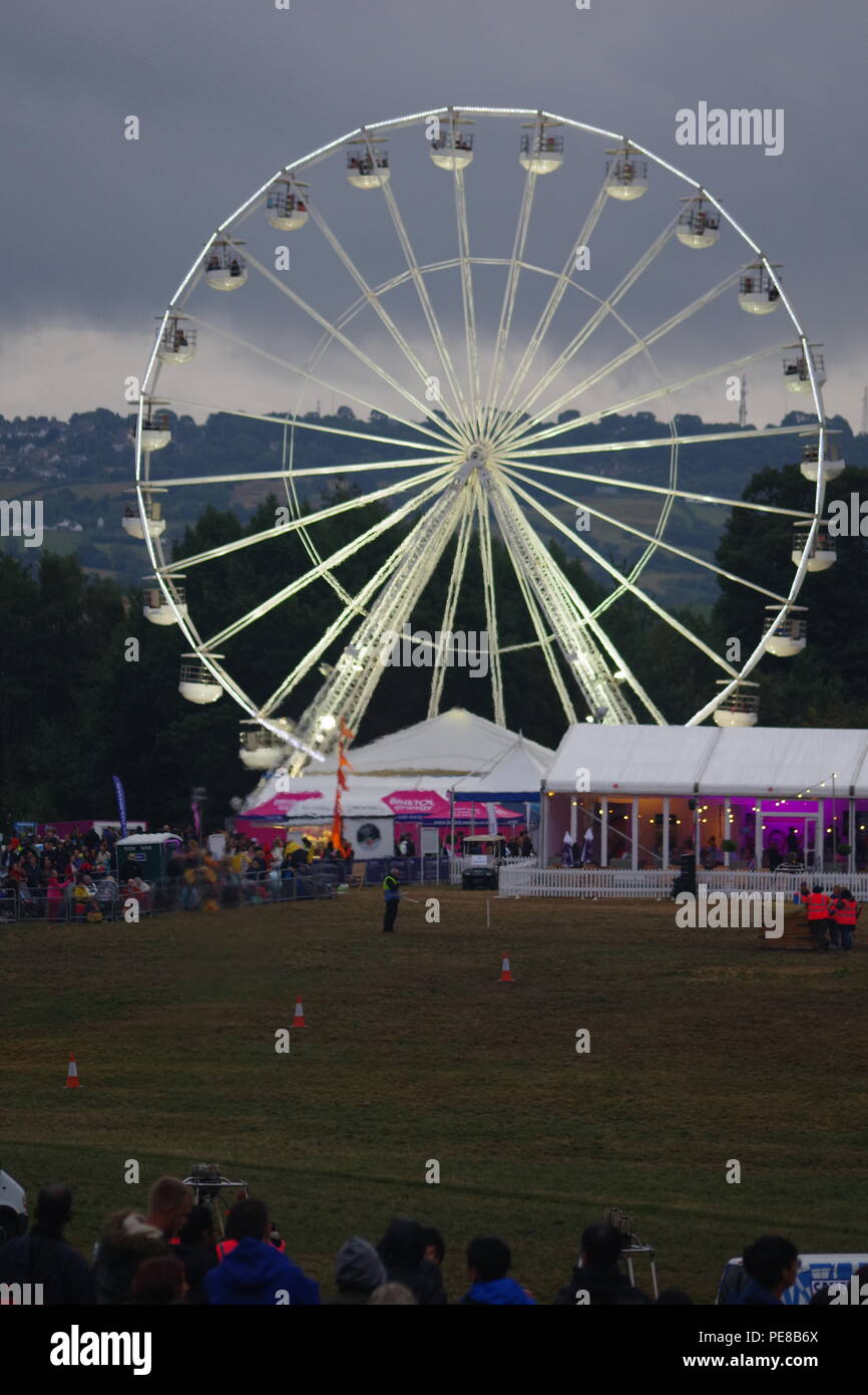 Illuminated Ferris wheel by tents on a grey evening. Bristol ...