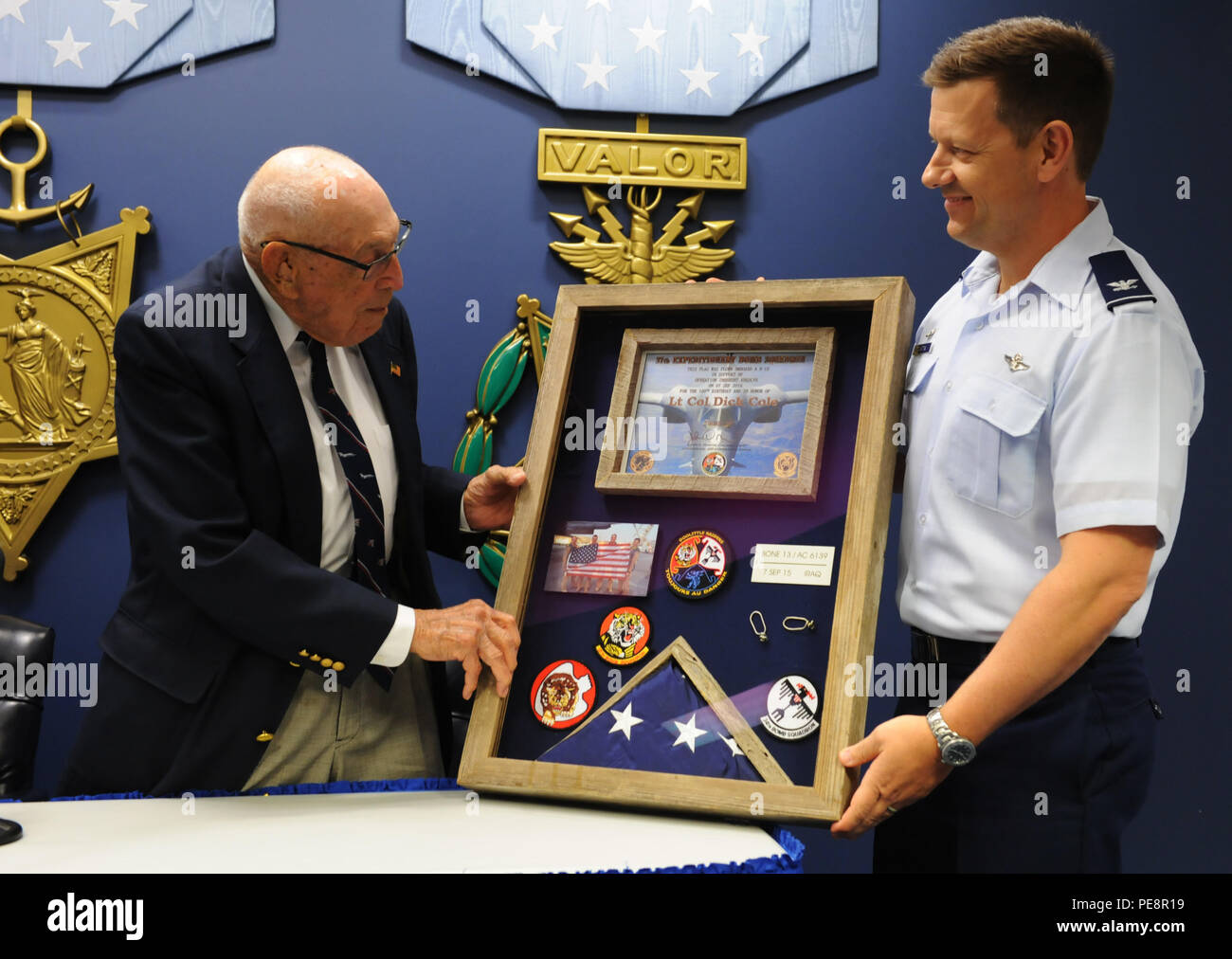 Retired Lt. Col. Robert E. Cole accepts a shadow box from Col. John ...