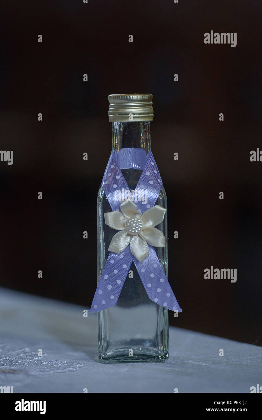 Glass recipient decorated with flowers and ribbons positioned against a ...