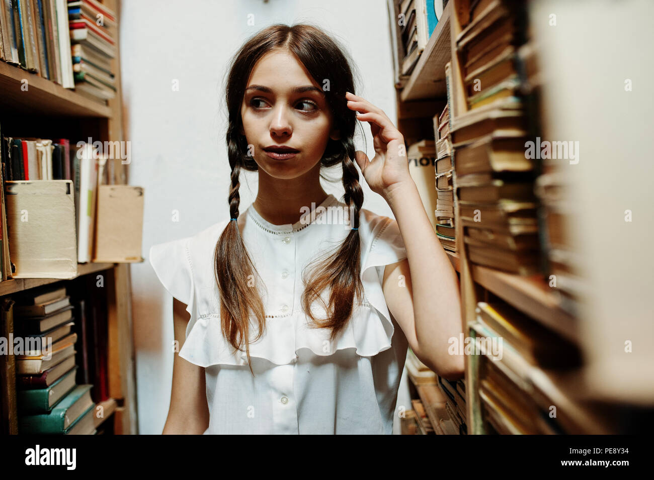 Girl with pigtails in white blouse at old library Stock Photo - Alamy