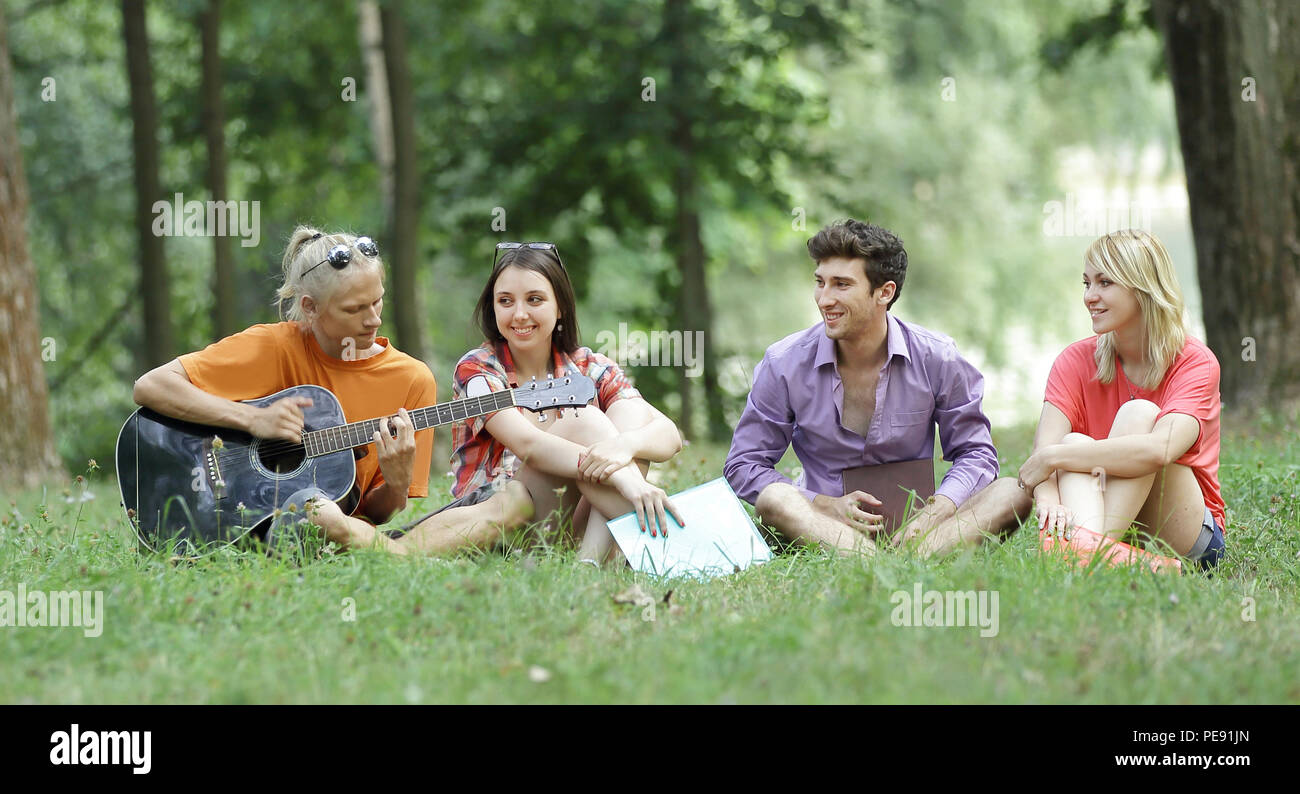 group of students sing songs sitting on the lawn in the city Park Stock ...