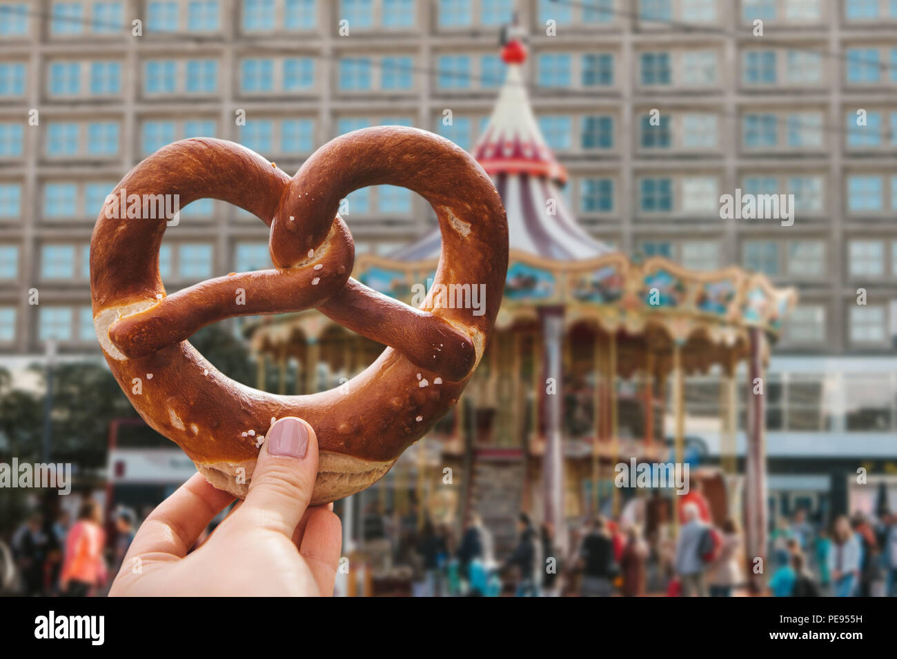 The girl is holding a traditional German pretzel. Carousel or merry-go ...