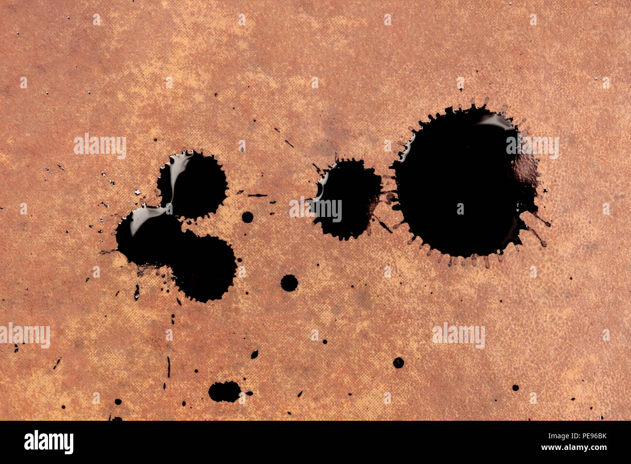 A splash of black ink on a brown texture, a grunge background with copy ...
