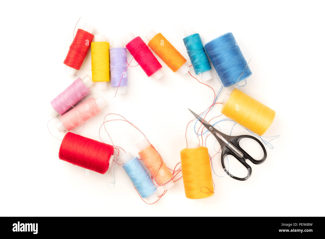 An overhead photo of vibrant threads and scissors on a white background ...