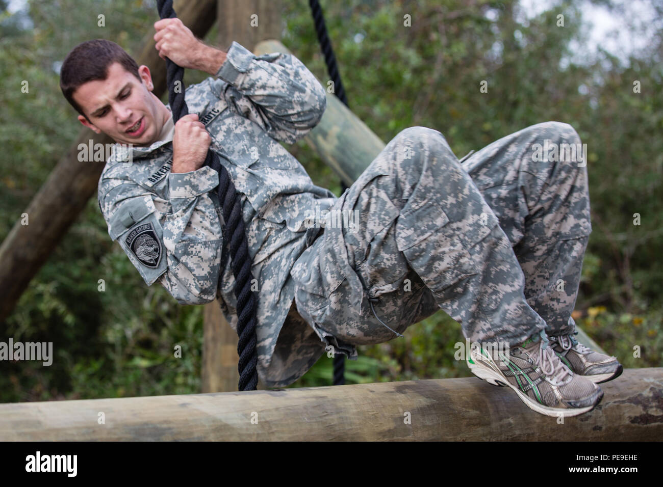 An Army Junior Officer Training Corps cadet uses a rope to swing over a ...