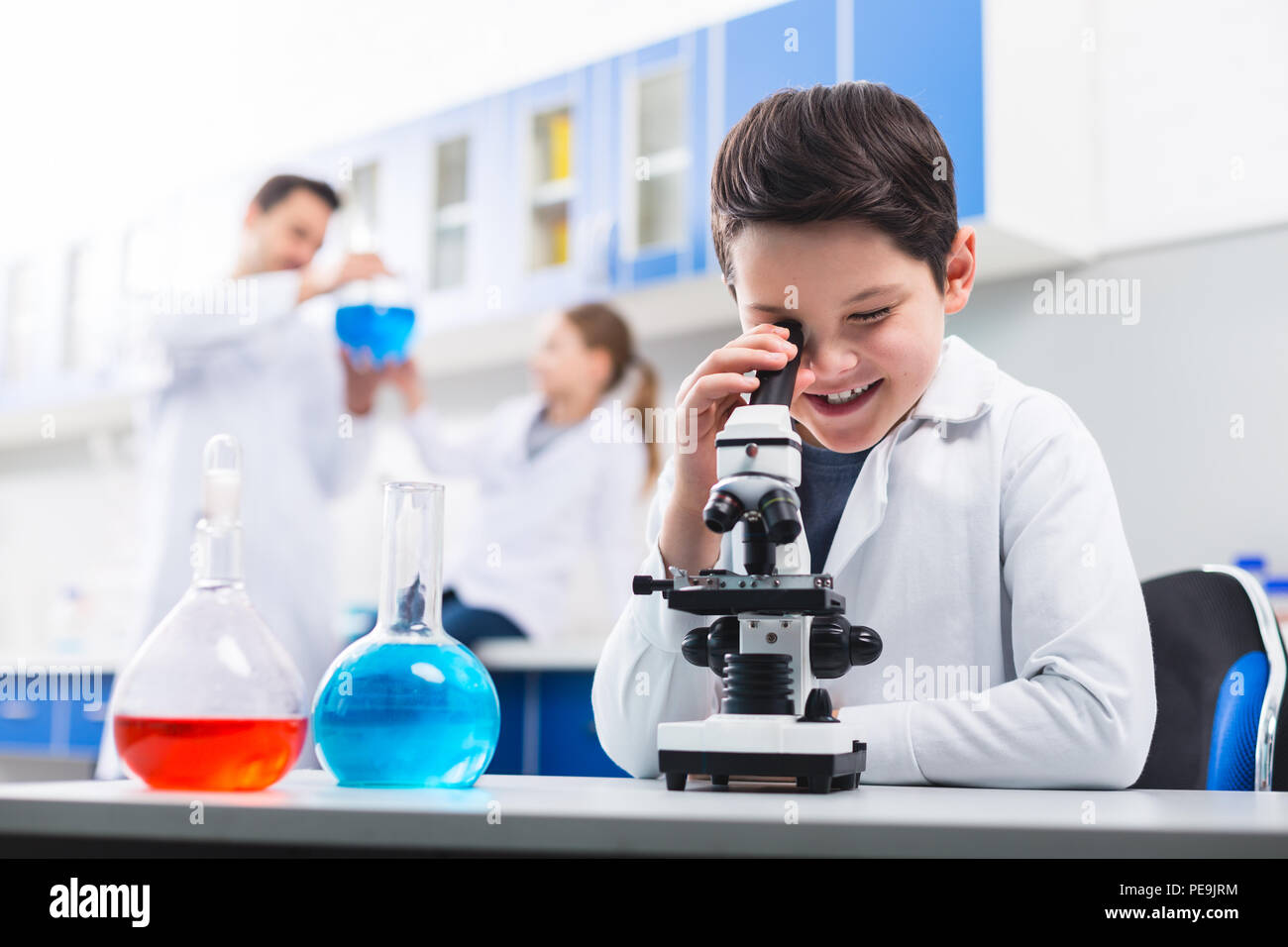 Interesting sample. Creative happy merry boy using microscope while ...