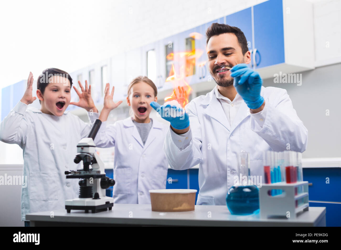 Magic in lab. Amazed shocked astonished kids rising hands and shouting ...