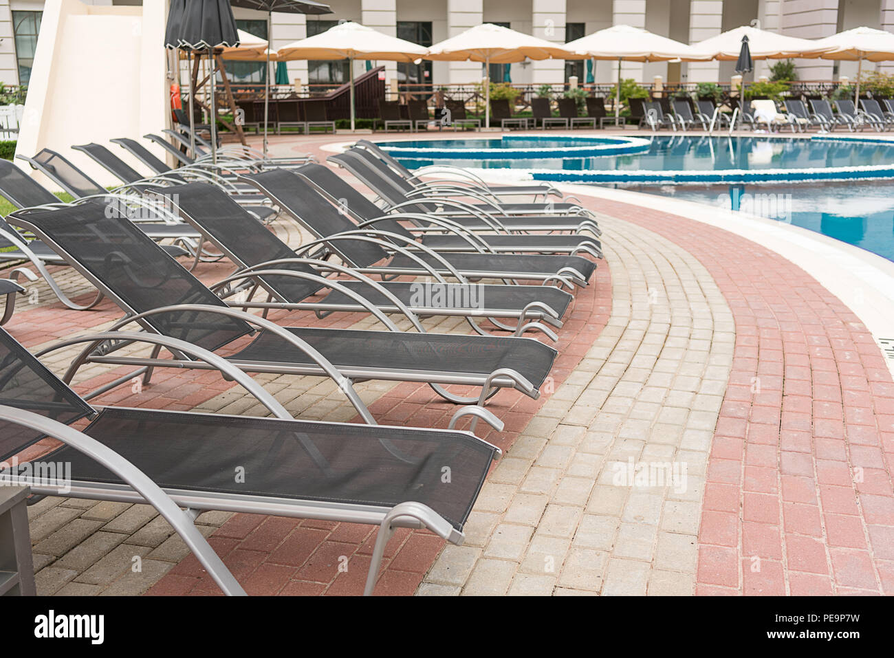 Sun beds at the edge of the pool Stock Photo - Alamy