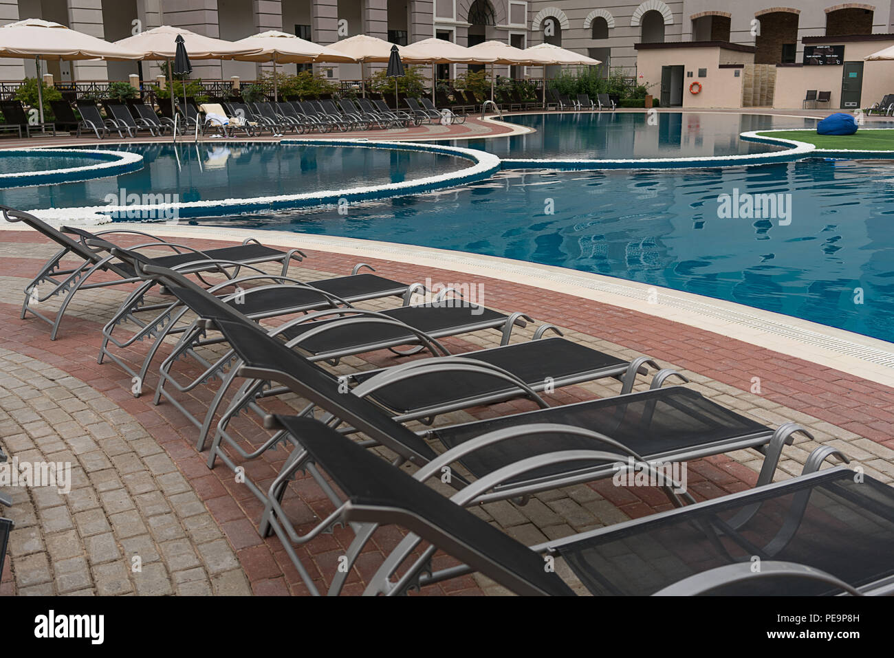 Sun beds at the edge of the pool Stock Photo - Alamy