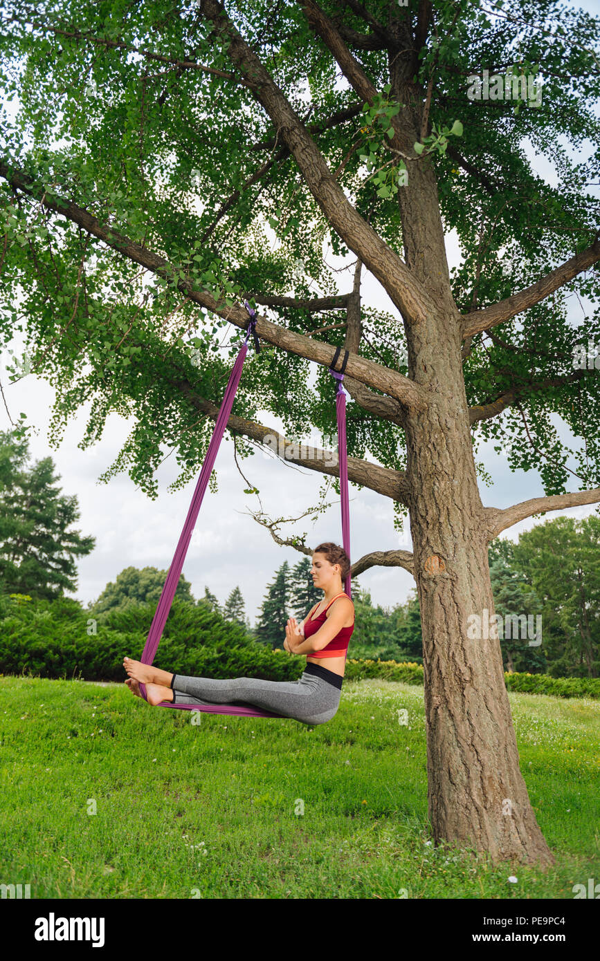 Dark-haired professional yoga teacher showing amazing fly yoga asana ...