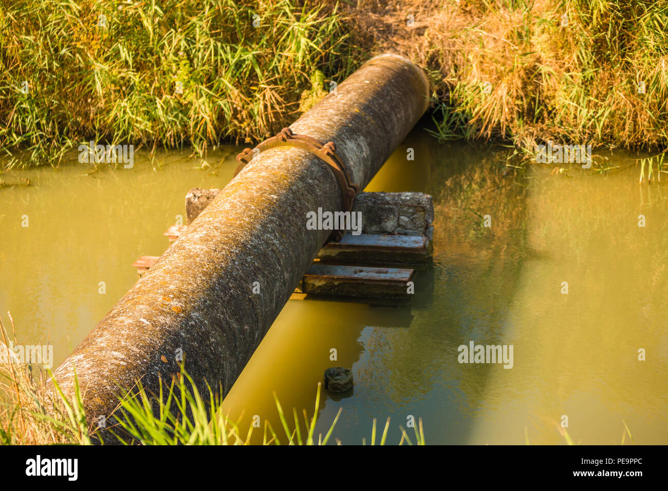 Old rusty and encrusted pipe for water sampling from irrigation channel ...