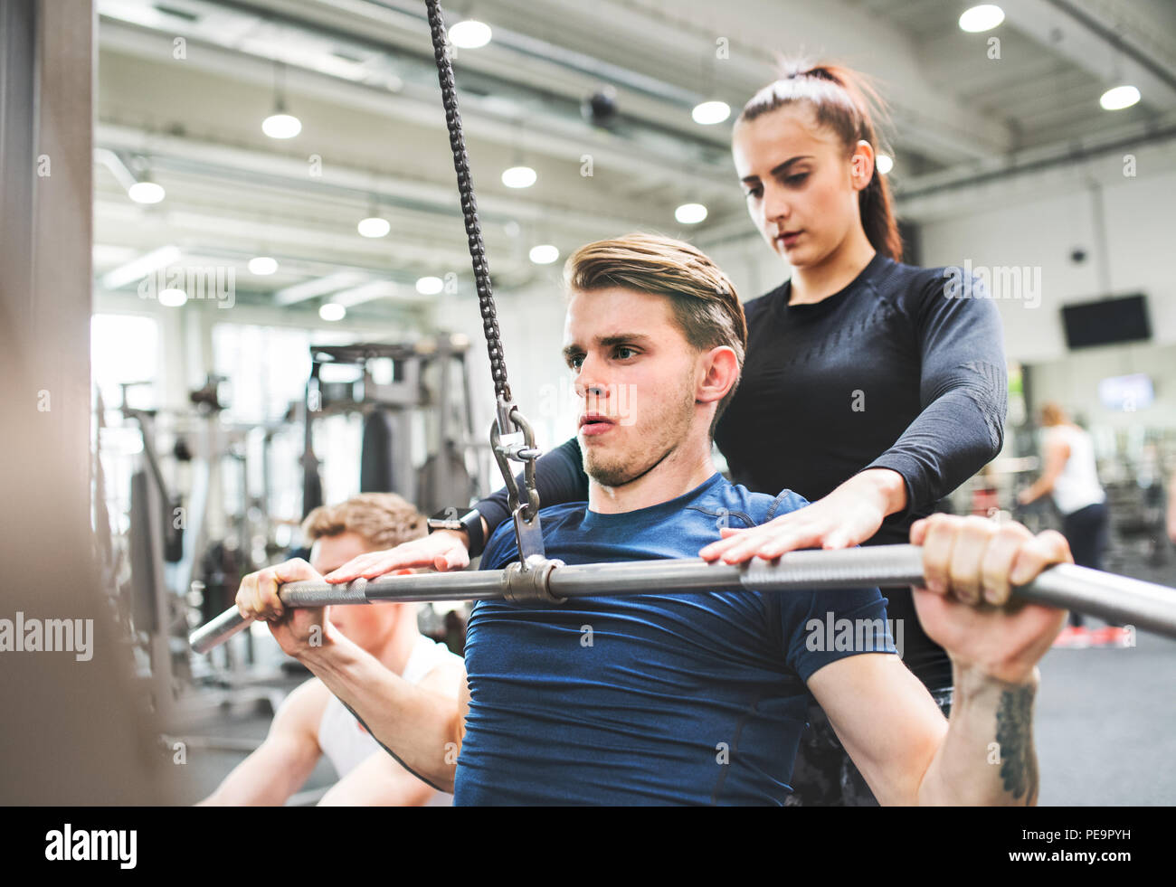 Young handsome fit man working out on pull-down machine in gym a ...