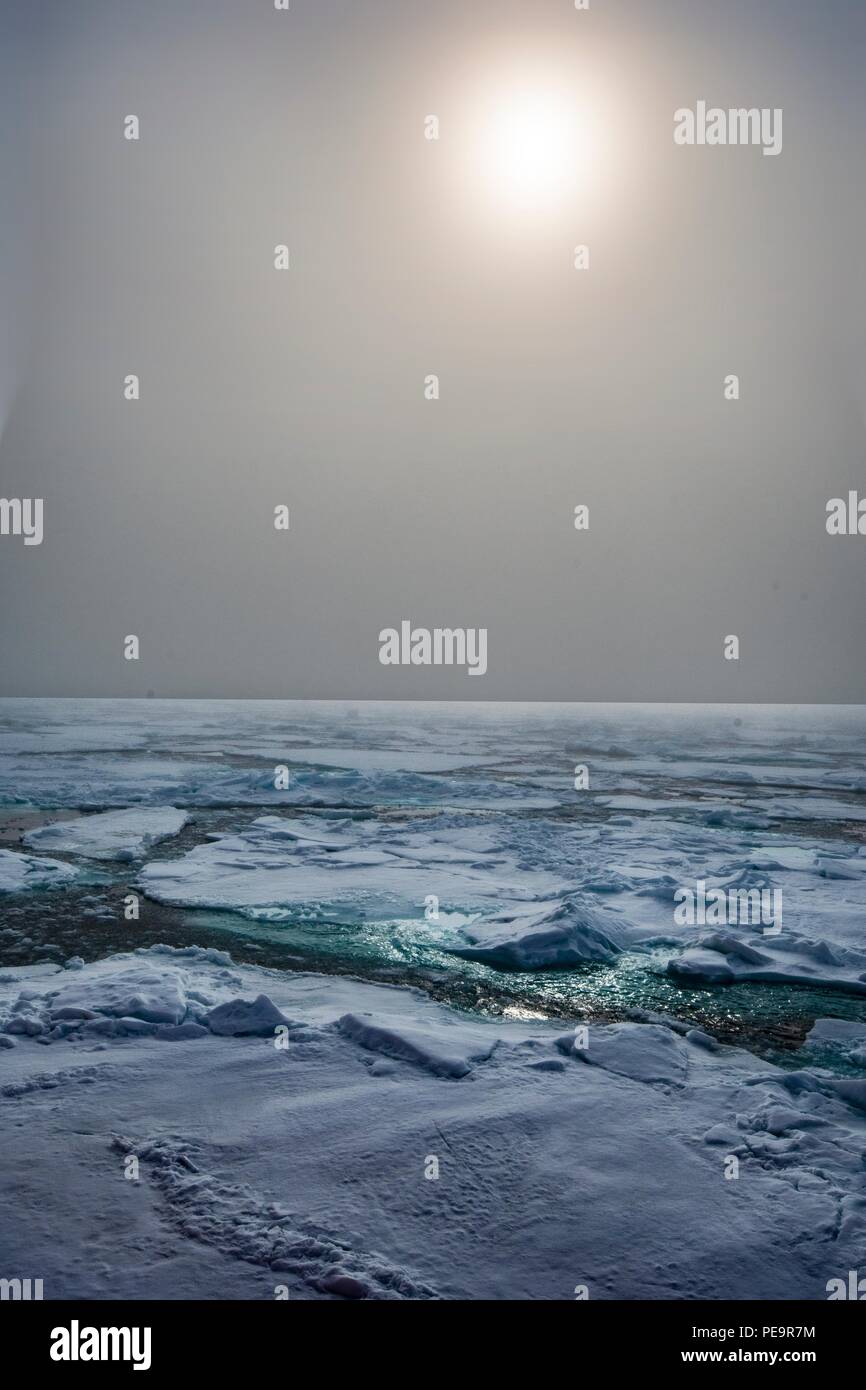 breaking through the sea ice, with the sun behind the fog, Deep blues ...
