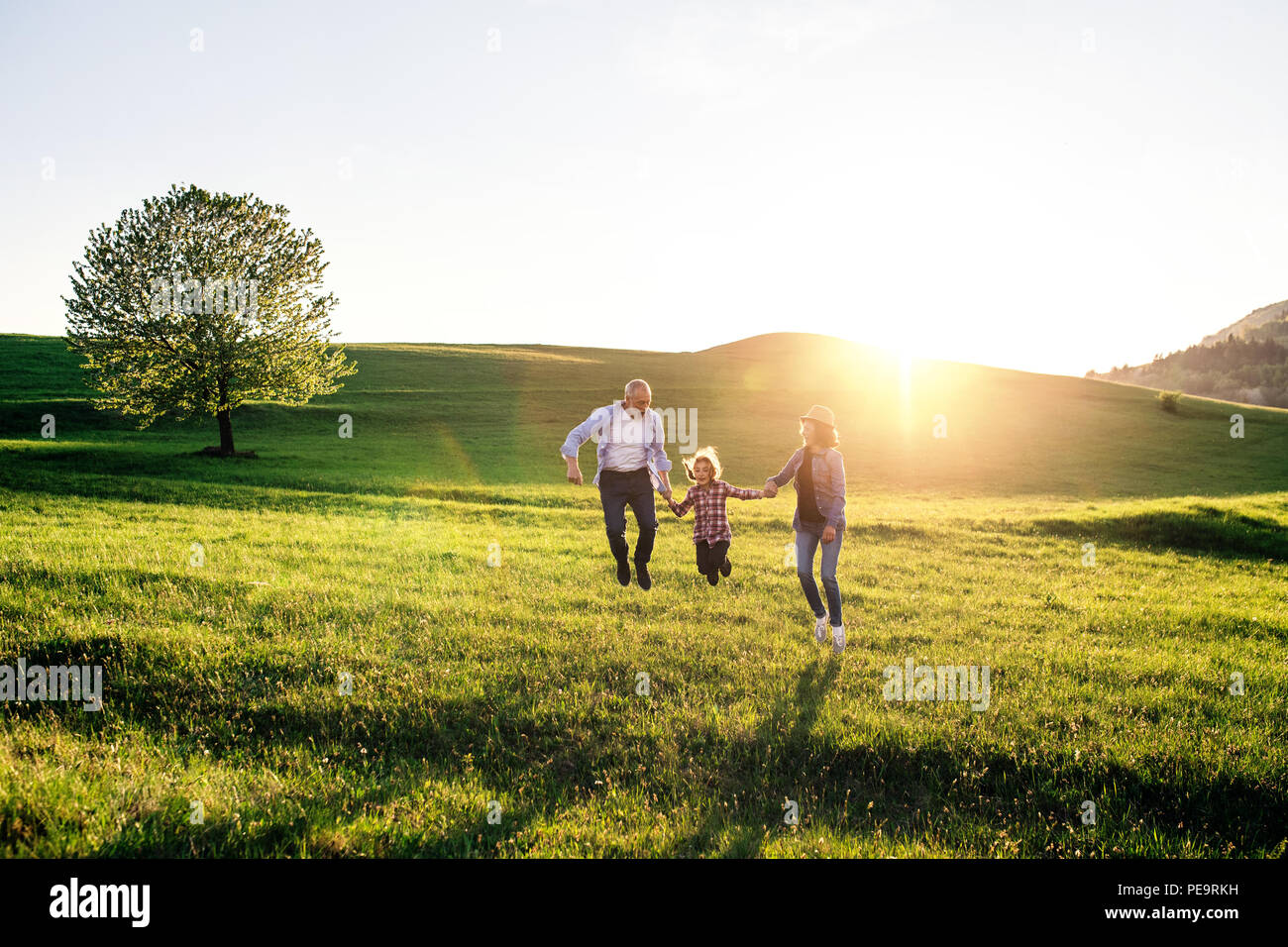 Senior couple with granddaughter on a walk outside in spring nature ...