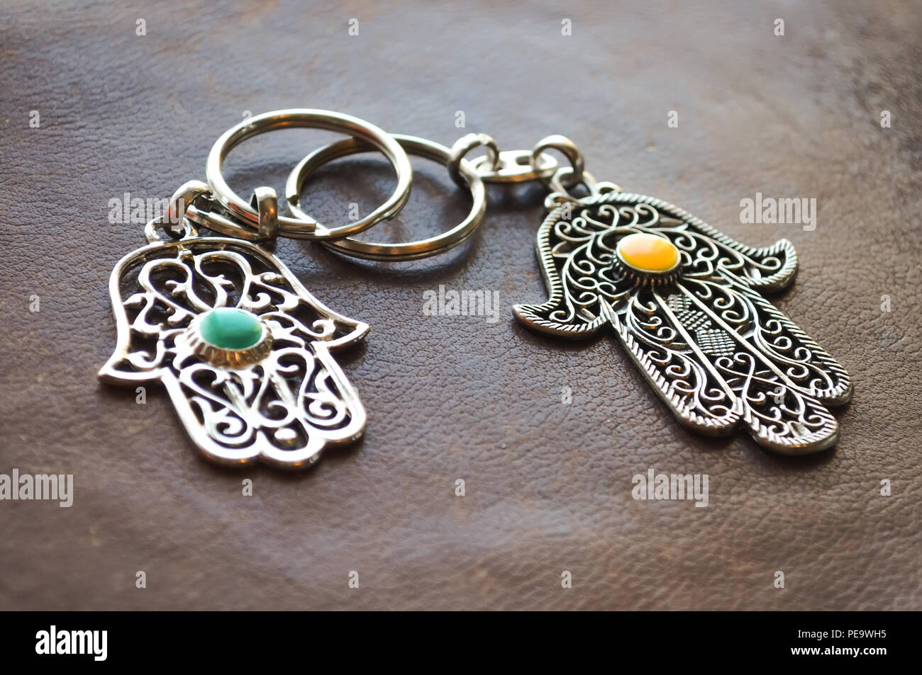 Two key rings in the form of Fatima Hand on a brown leather background ...