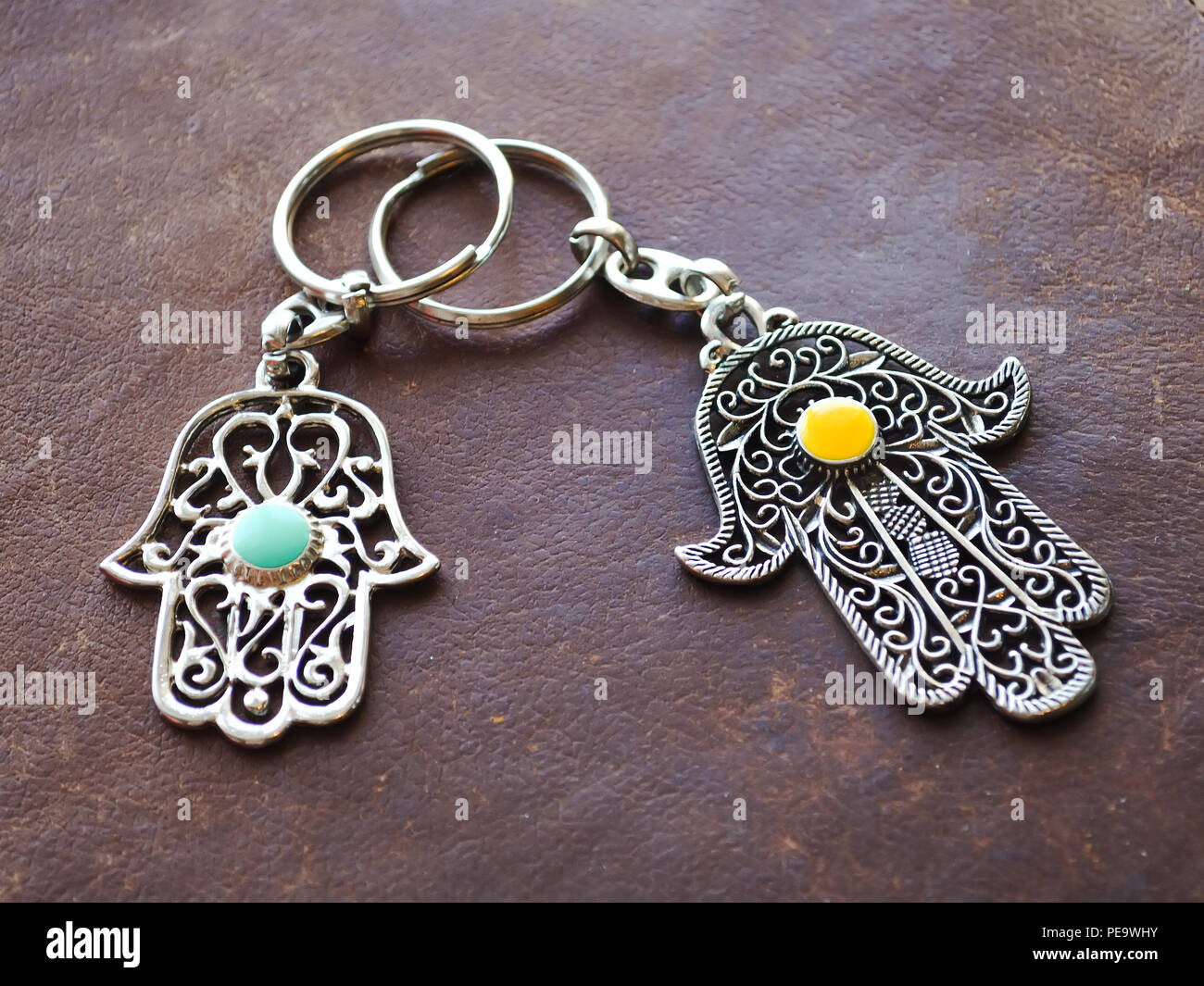 Two key rings in the form of Fatima Hand on a brown leather background ...