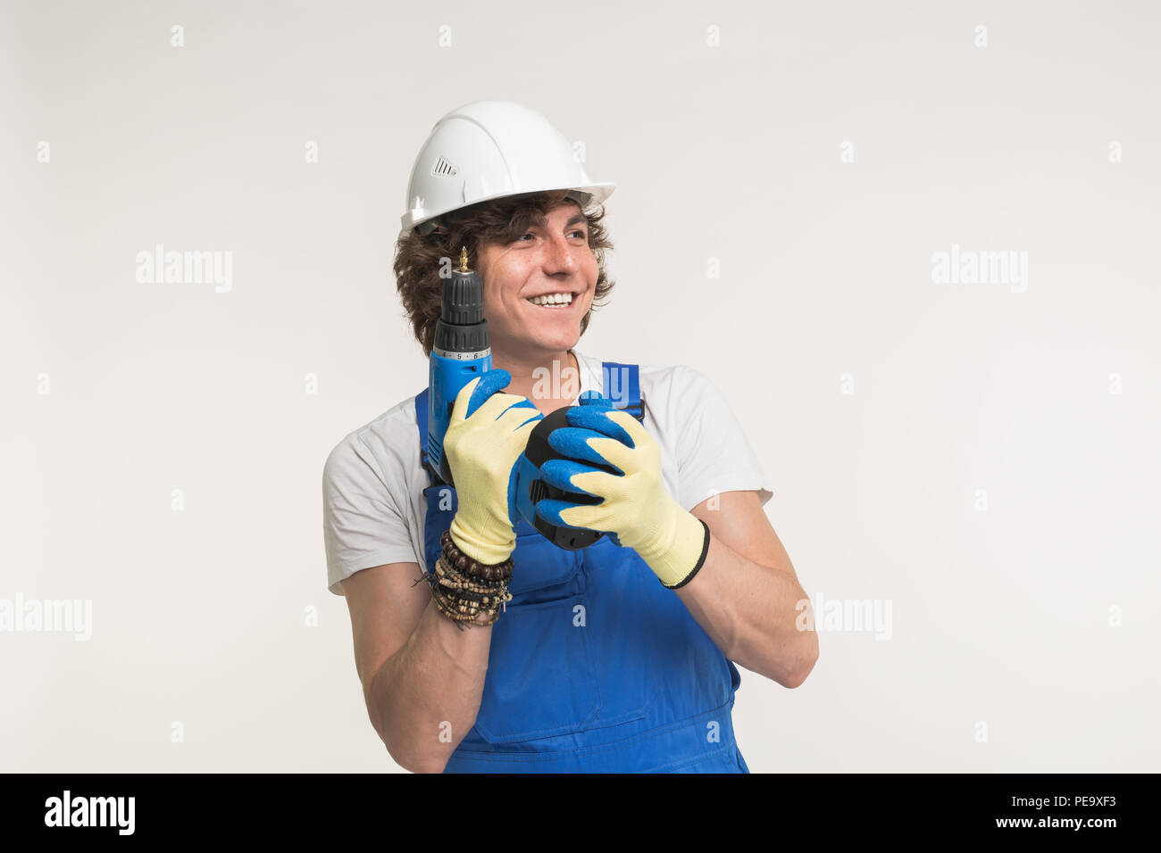 Portrait of handsome happy builder with skrewdriver on white background ...