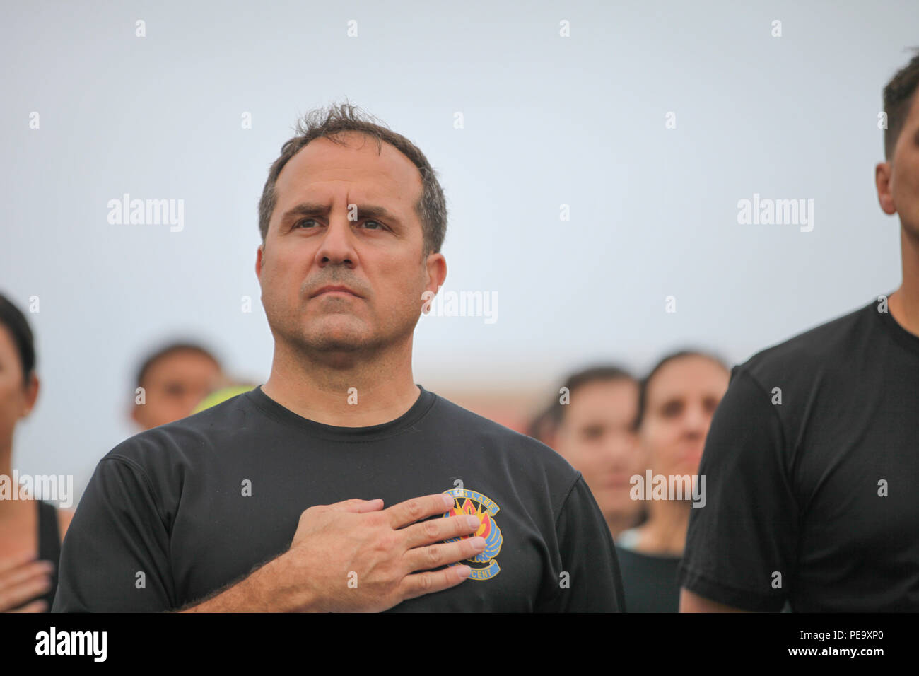 Participants and volunteers stand solemnly with their hands over their ...