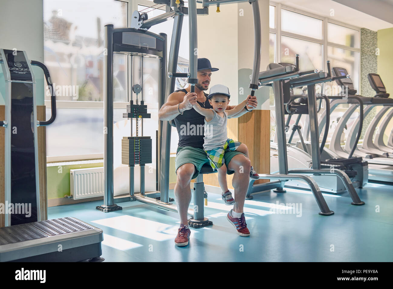 Fit father training hands and back on simulator keeping little son on ...