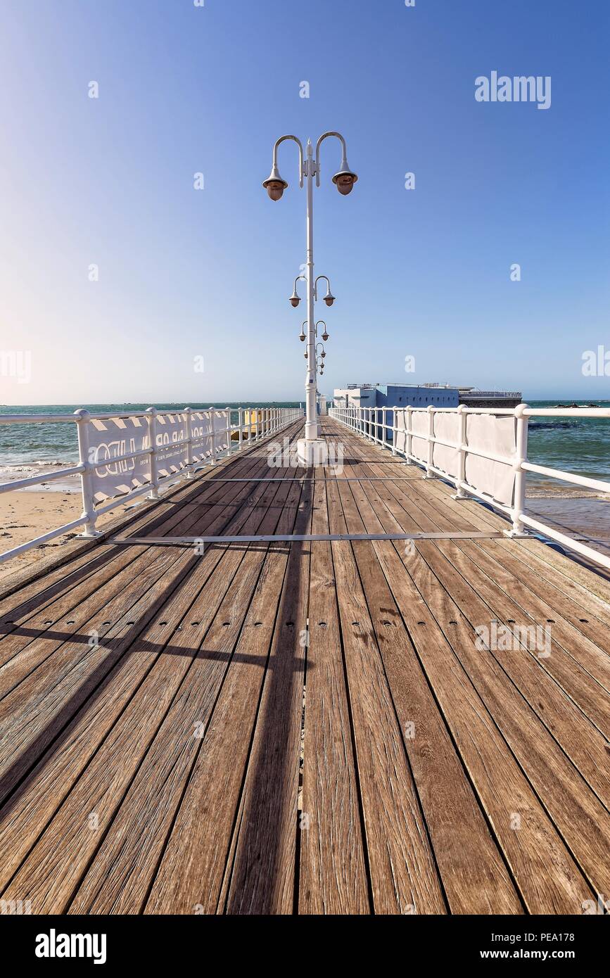 The pier at St Helier beach, Jersey. Wooden planks stretch forward with ...