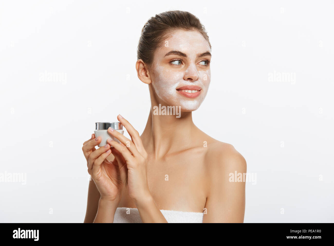 Young woman putting cream on her face isolated on white background ...