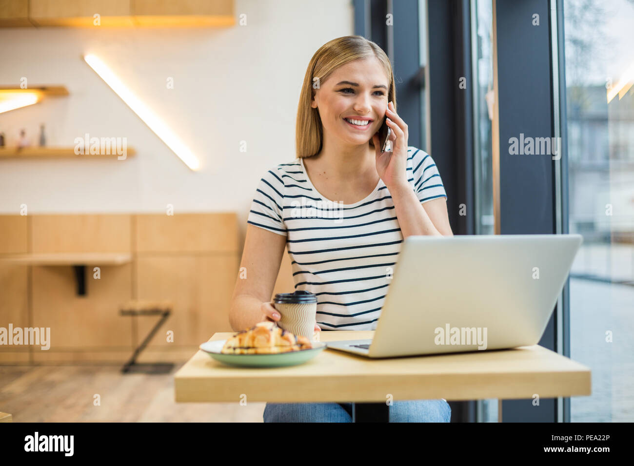 Distance communication. Positive joyful young woman sitting in the cafe ...