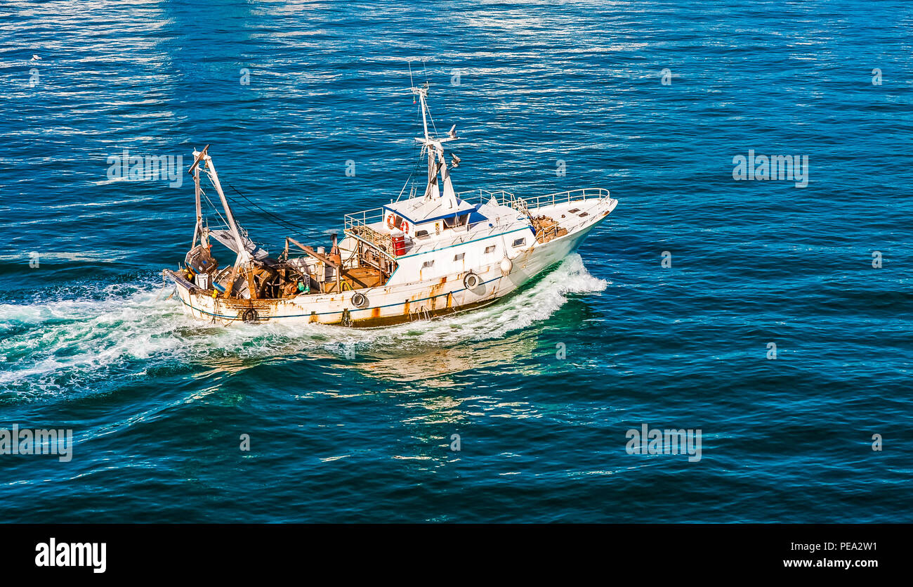 An old fishing boat cruising across a calm bay Stock Photo - Alamy
