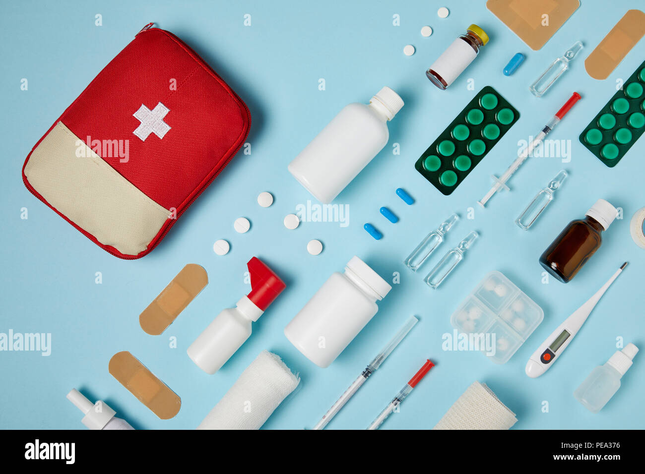 top view of first aid kit bag with composed medicines on blue surface ...