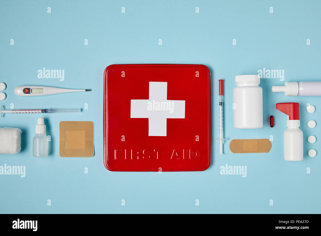 top view of red first aid kit box on blue surface with medical supplies ...