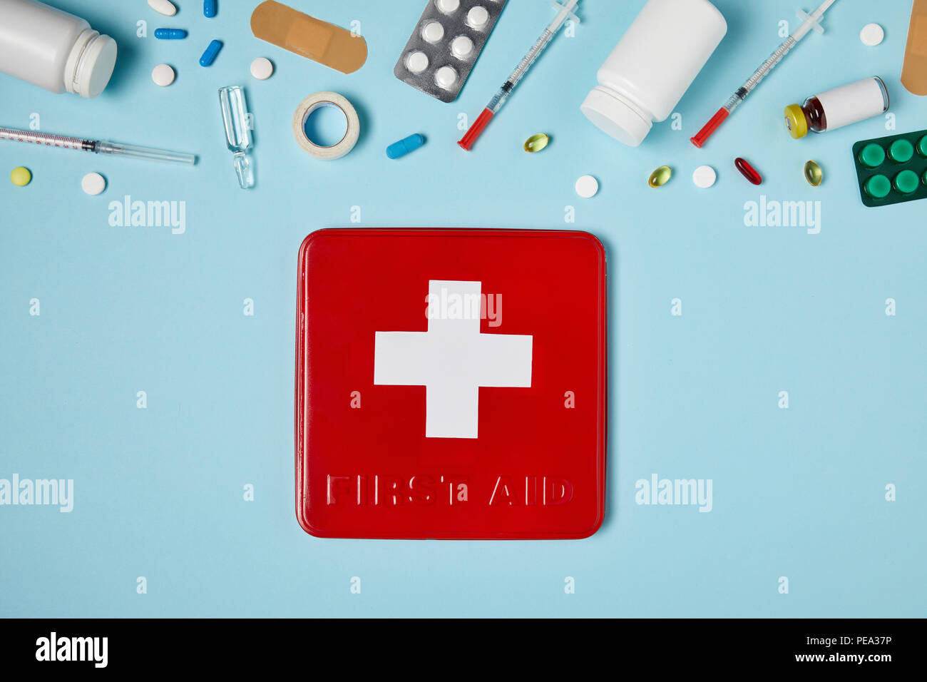 top view of red first aid kit box on blue surface with various ...