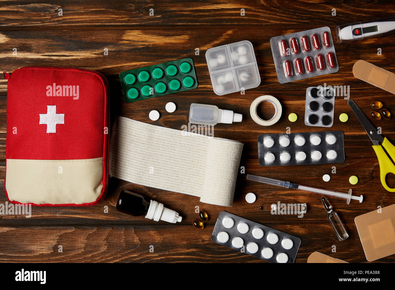 top view of first aid kit bag with various medicines on wooden tabletop ...