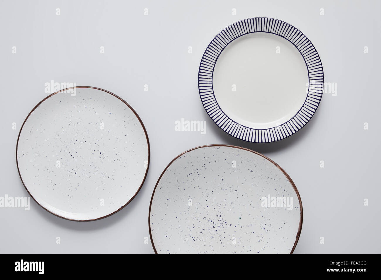 top view of three different ceramic plates on white table, minimalistic ...