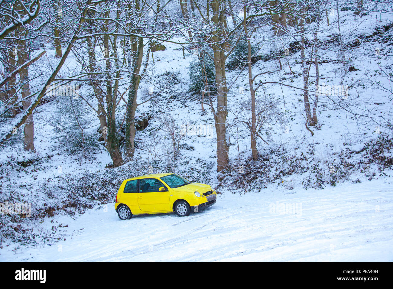 A Yellow VW Lupo car sits at the side of the road on a snowy day in the ...