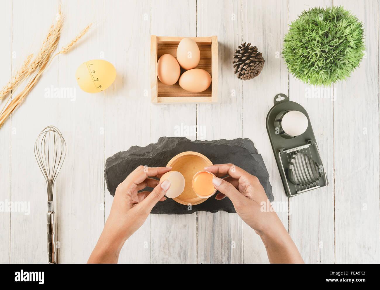 Top view of woman chef breaking an egg into the wood bowl. Cooking concept Stock Photo - Alamy