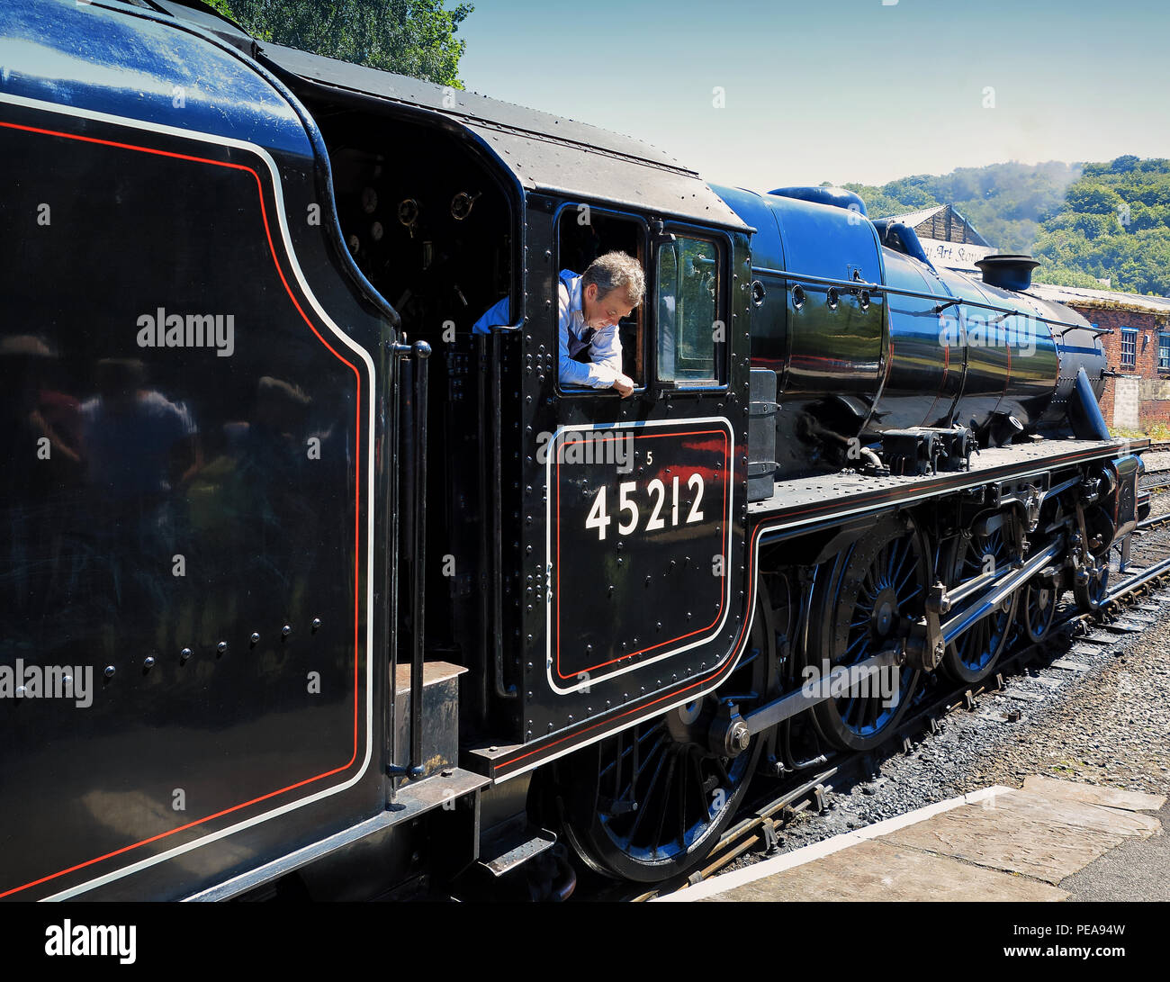 The driver of a black steam engine waits to set of from Keighley ...