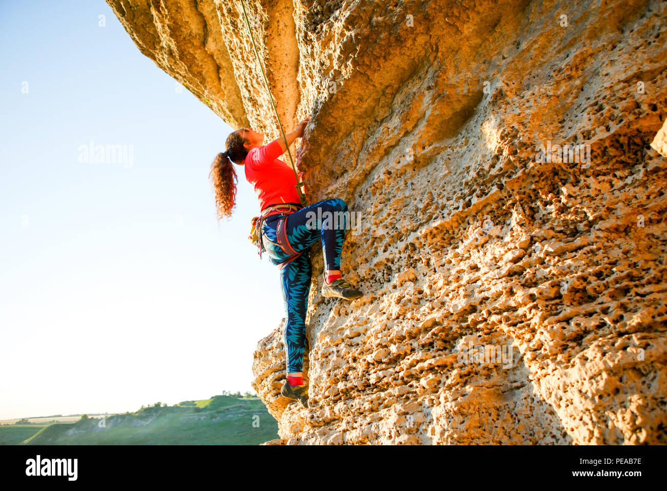 Picture of curly-haired female tourist clambering over rock Stock Photo ...